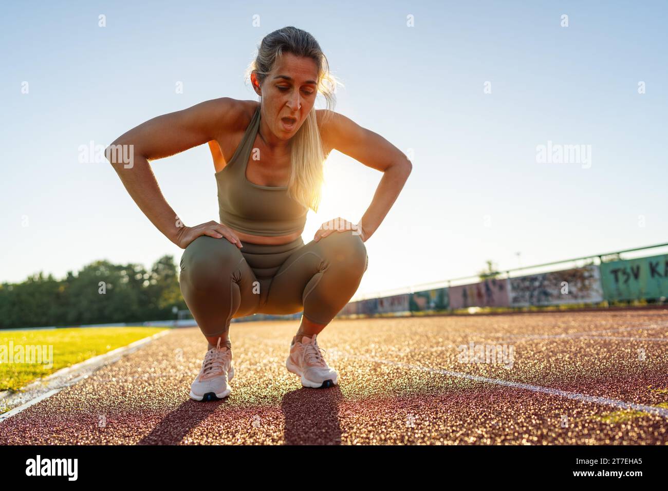 Tired female athlete resting on track field after workout Stock Photo - Alamy