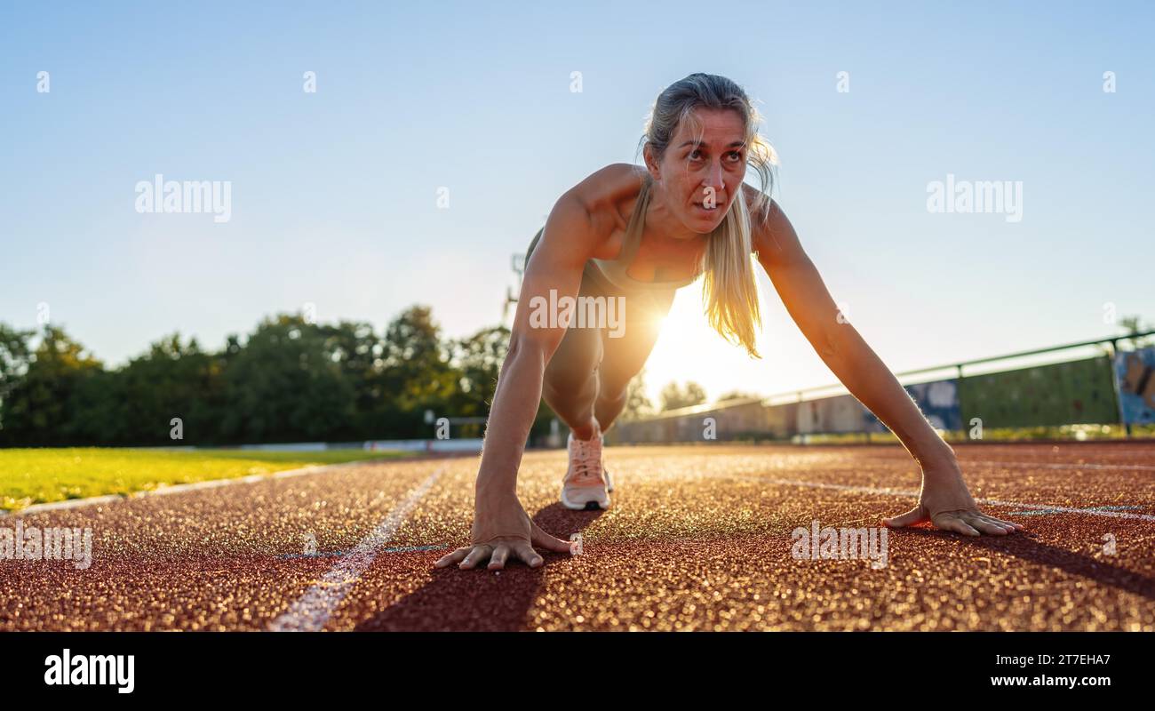Determined female athlete in starting position on running track Stock ...