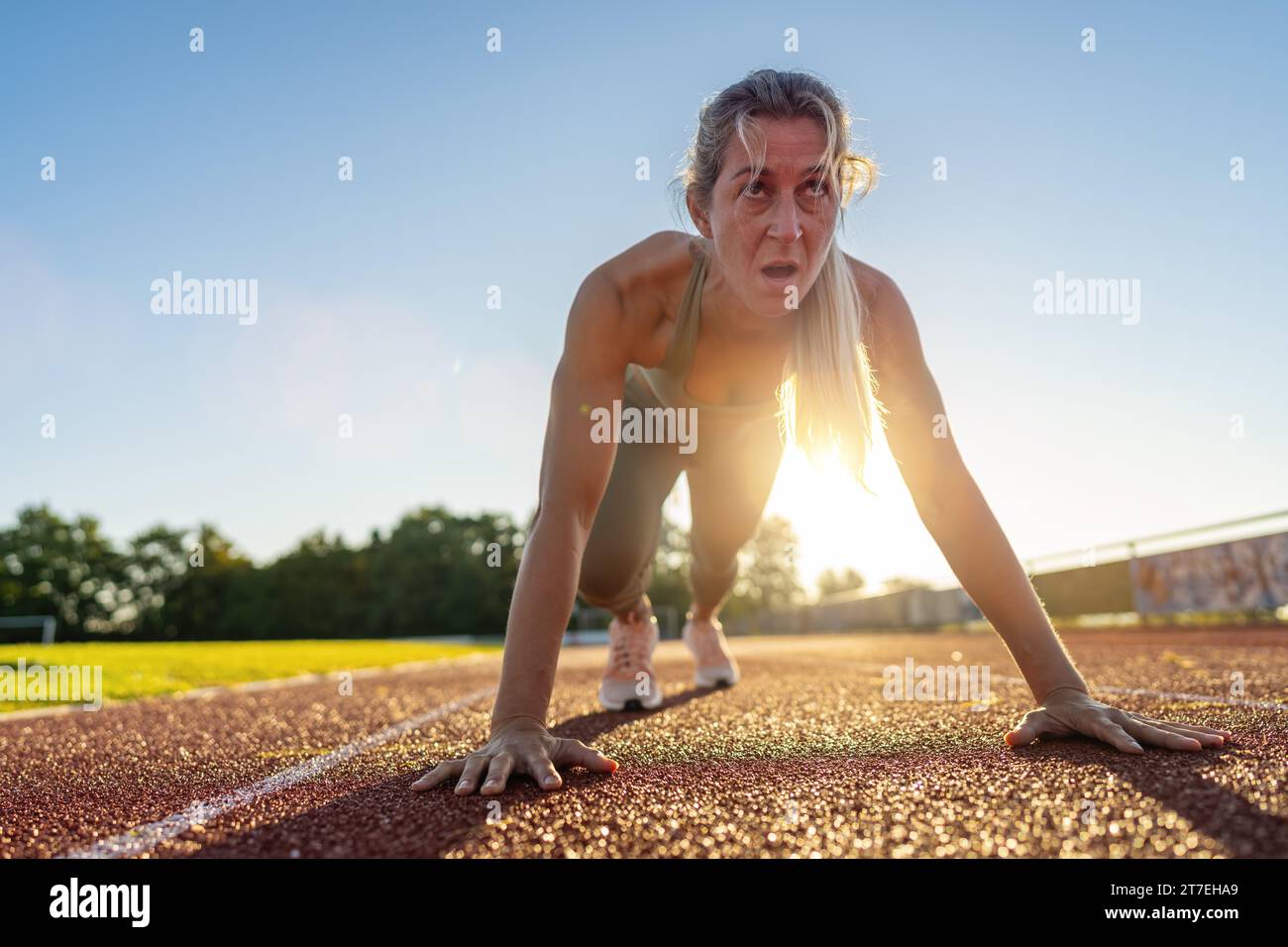 Determined female athlete in starting position on running track Stock ...