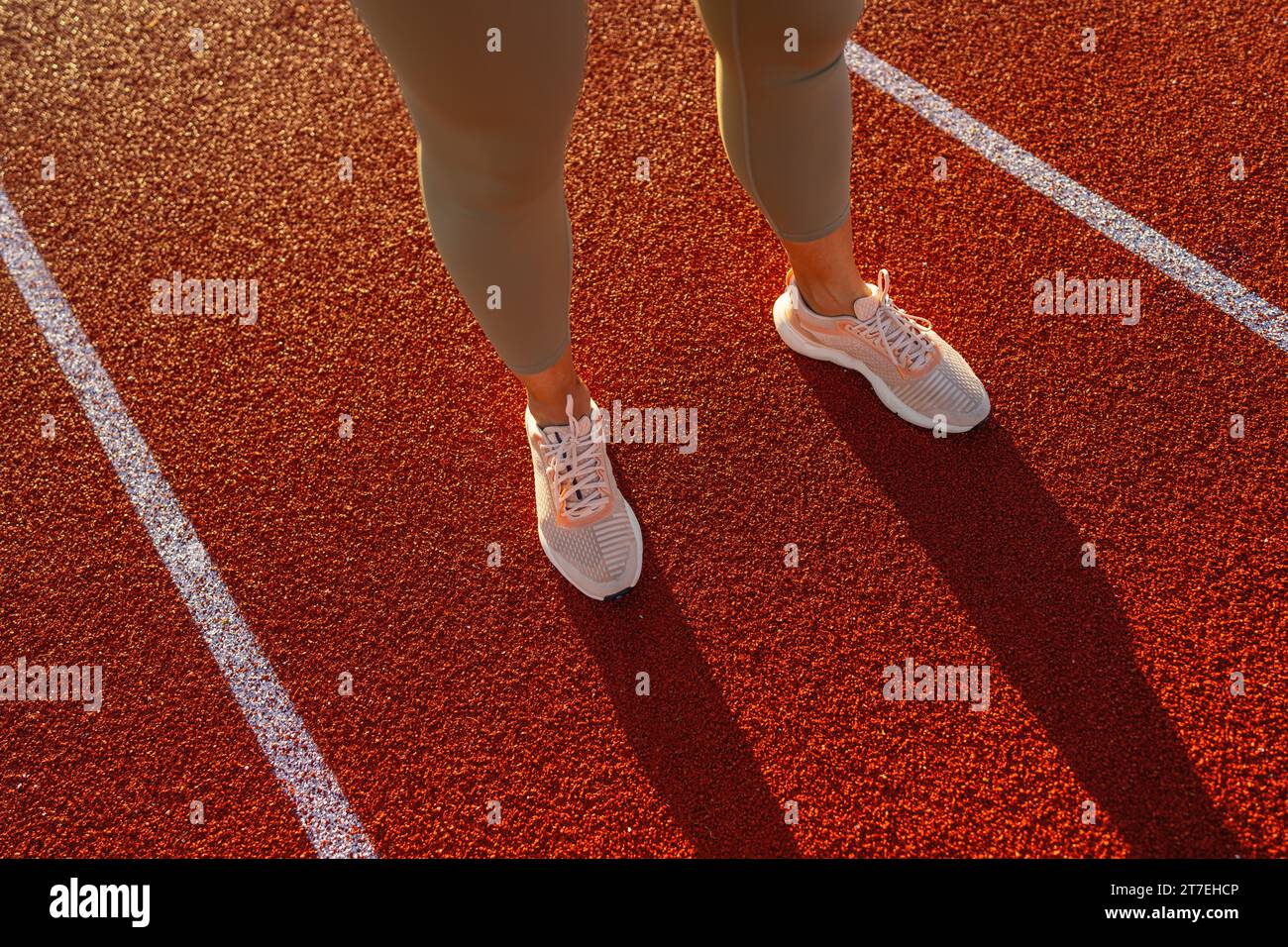 Close-up of female athlete's legs on starting line of running track ...