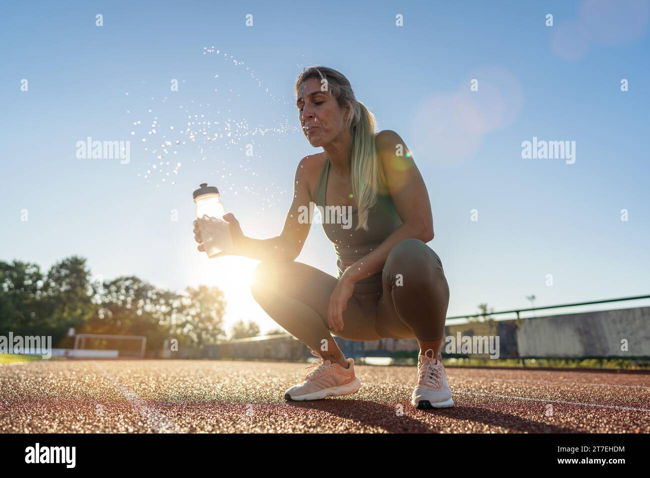 Athlete woman spitting water from mouth and holding water bootle while ...