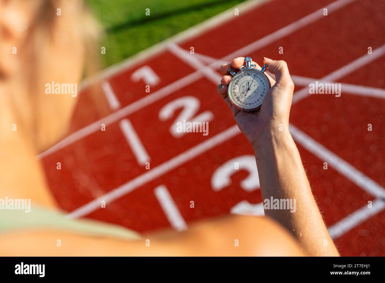 Over-the-shoulder view of a person holding a stopwatch at a running ...