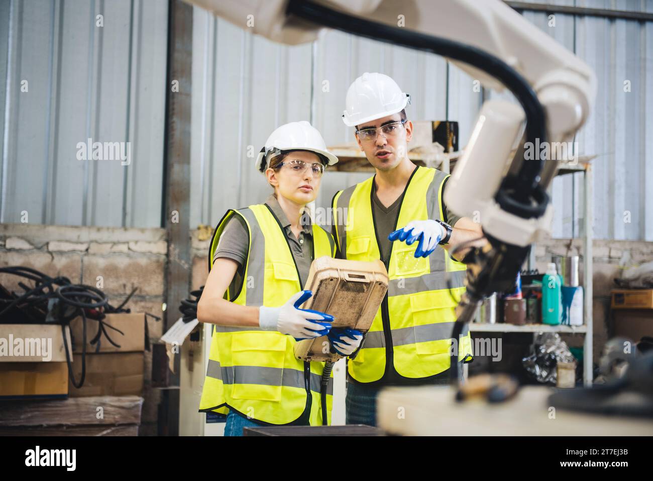 Engineers team mechanic using computer controller Robotic arm for welding steel in steel factory ...
