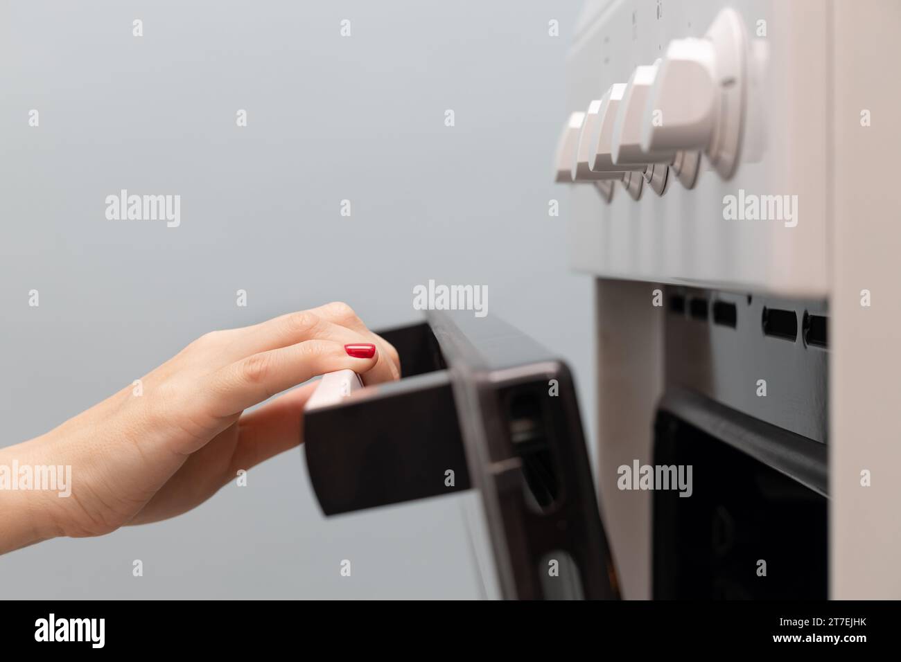 woman's hand opens the oven door, shot with shallow depth of field ...