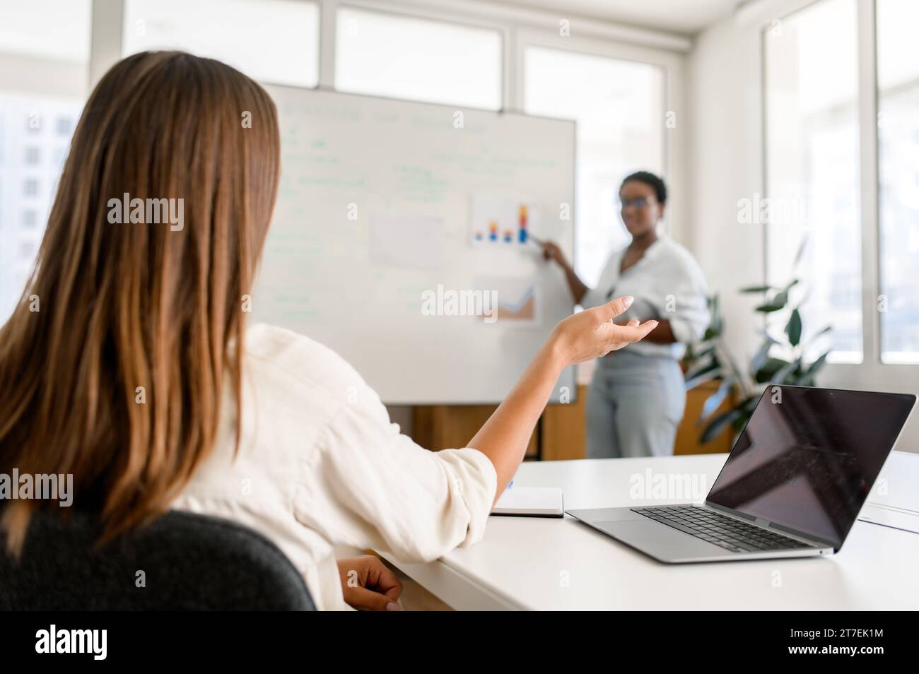 Female manager, coach, speaker or team lead standing near flipchart and ...