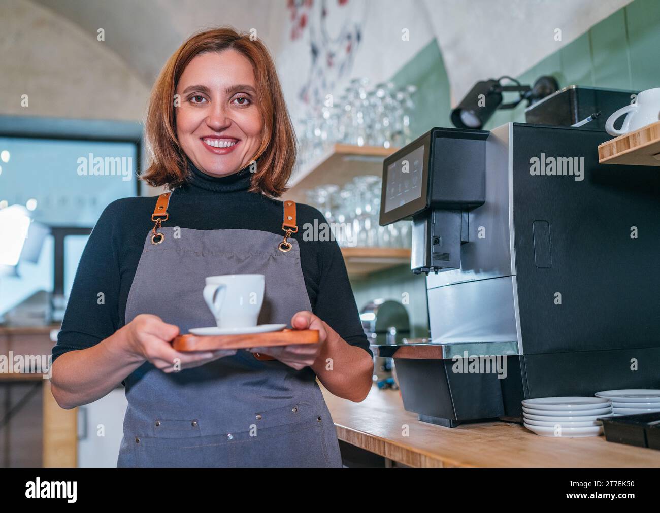 Cheerfully happy smiling Waitress near coffee machine carrying white ...
