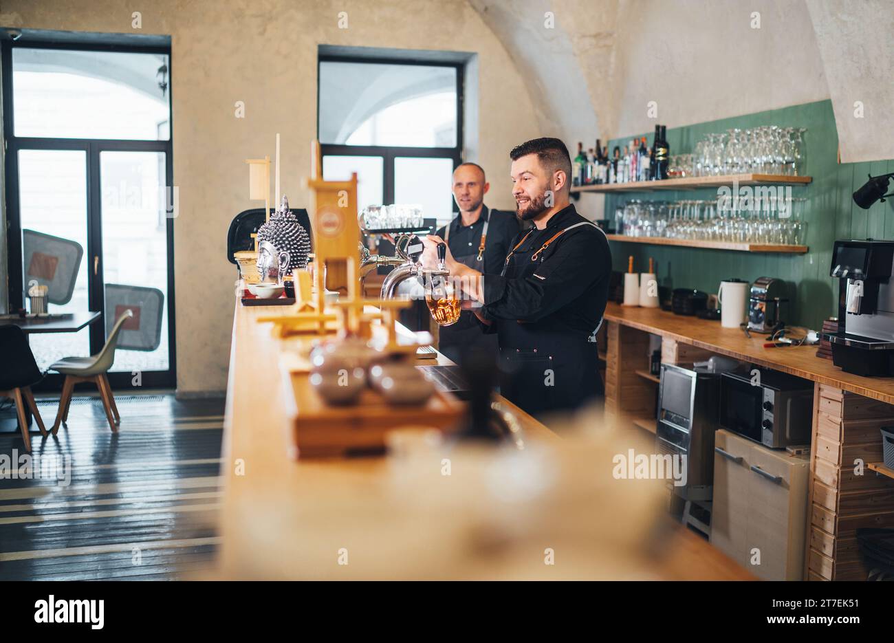 Two smiling caucasian men friends barman lager beer tapping and waiter ...