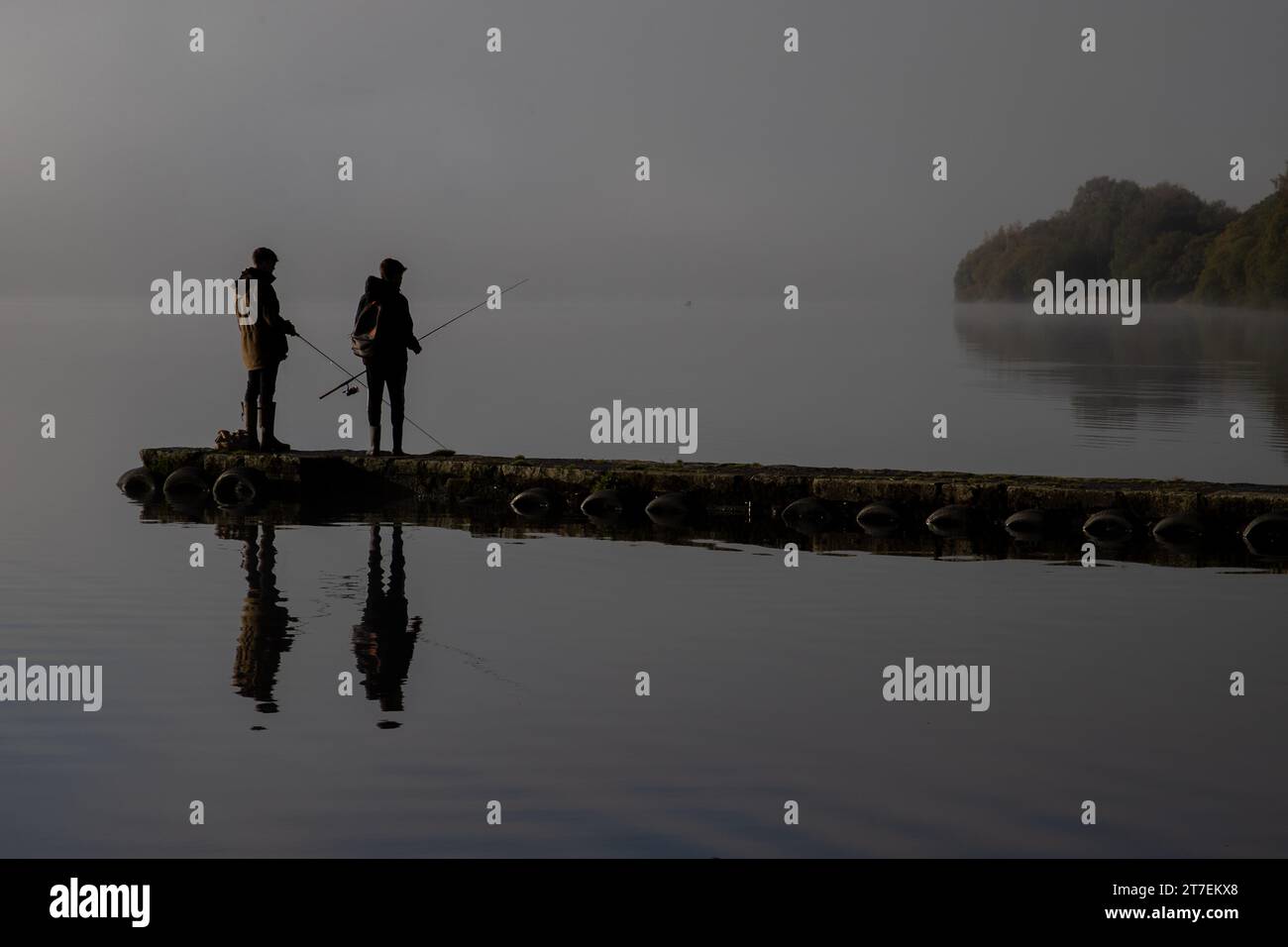 Two men fishing seen in silhouette on a misty morning on Lake Bala ...