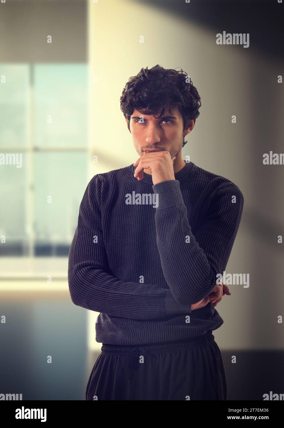 A man standing in a room with his hand on his chin. A Man Reflecting in ...