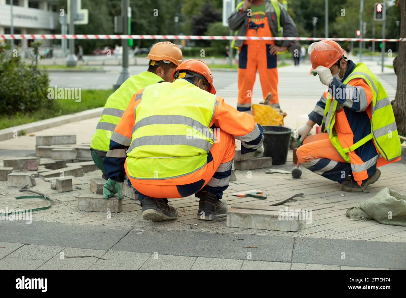 Workers make road. Repair of pedestrian zone. Three workers in helmets ...