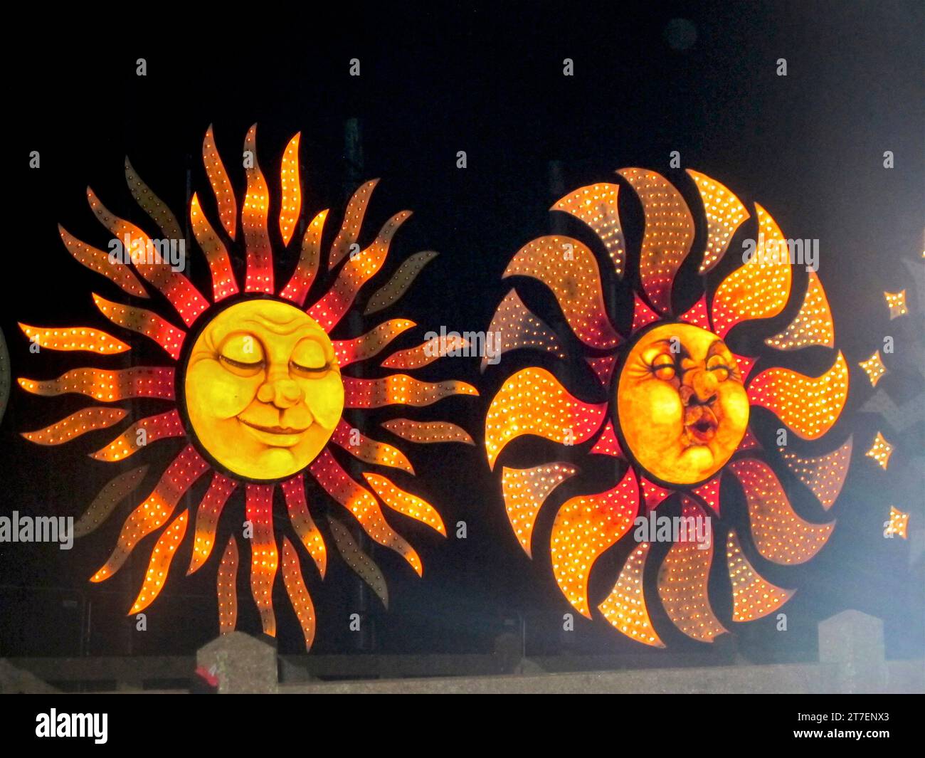 two orange and red illuminated sun figures on a seaside display Stock ...
