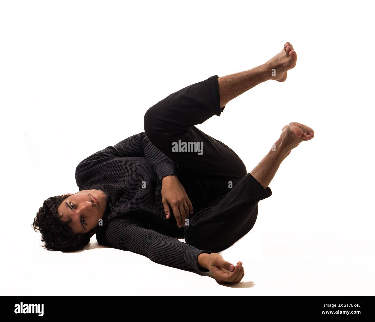 A young man laying, falling on the ground in a funny pose, looking at ...