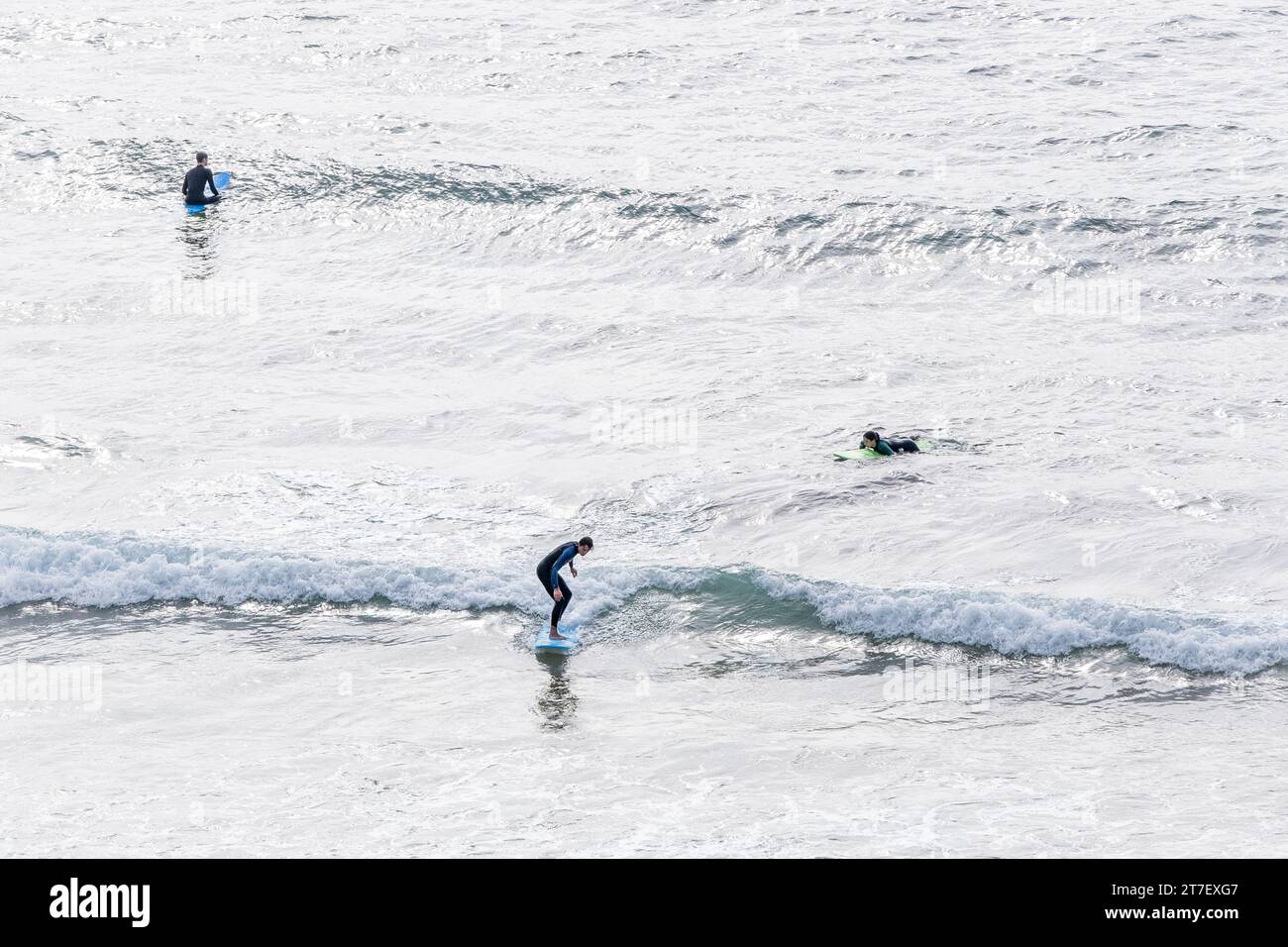 Coastal Harmony: Aerial View of Three Surfers Creating a Triangular ...