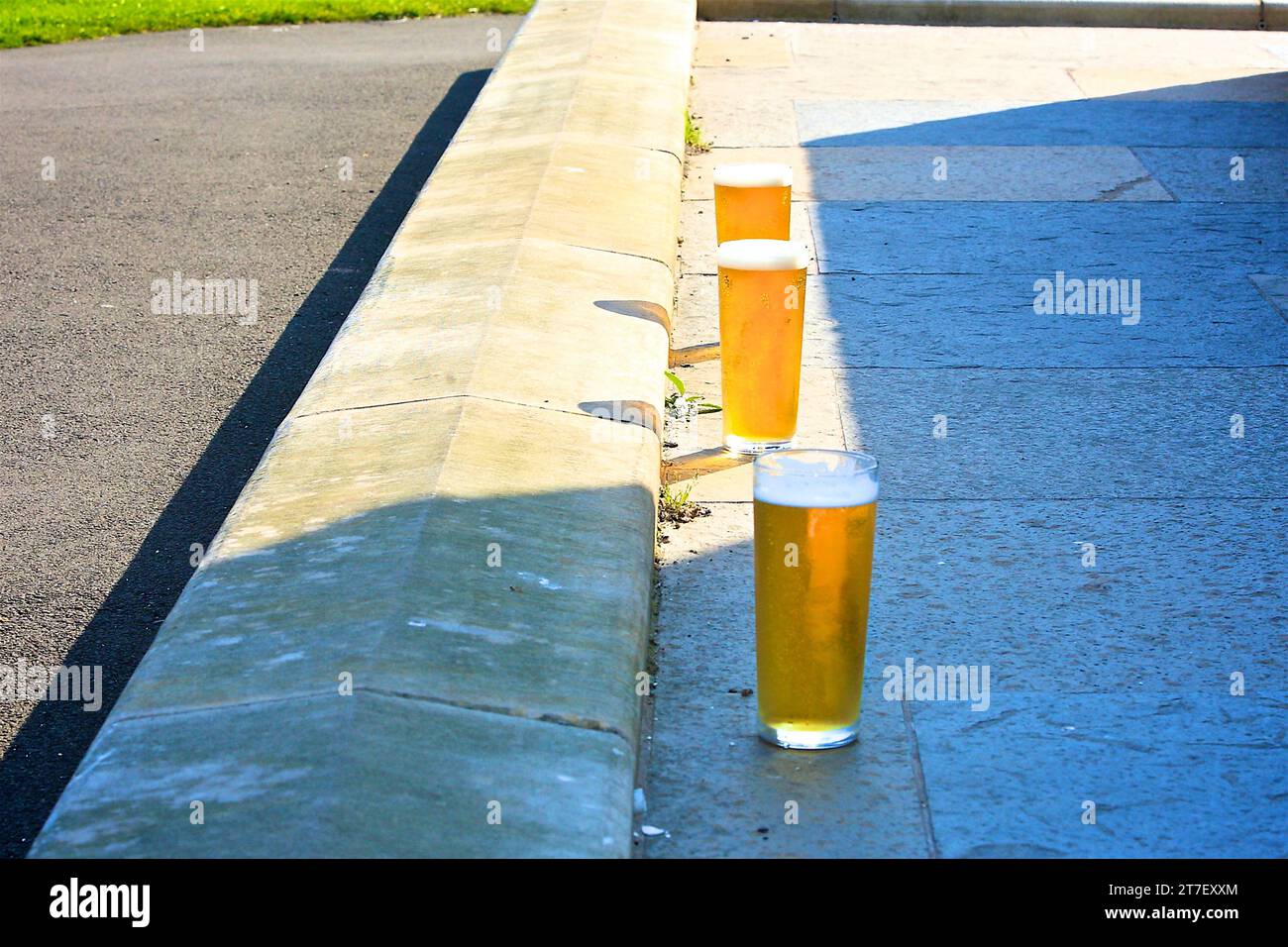 three pints of lager sat in a row on the ground on a summers day Stock ...