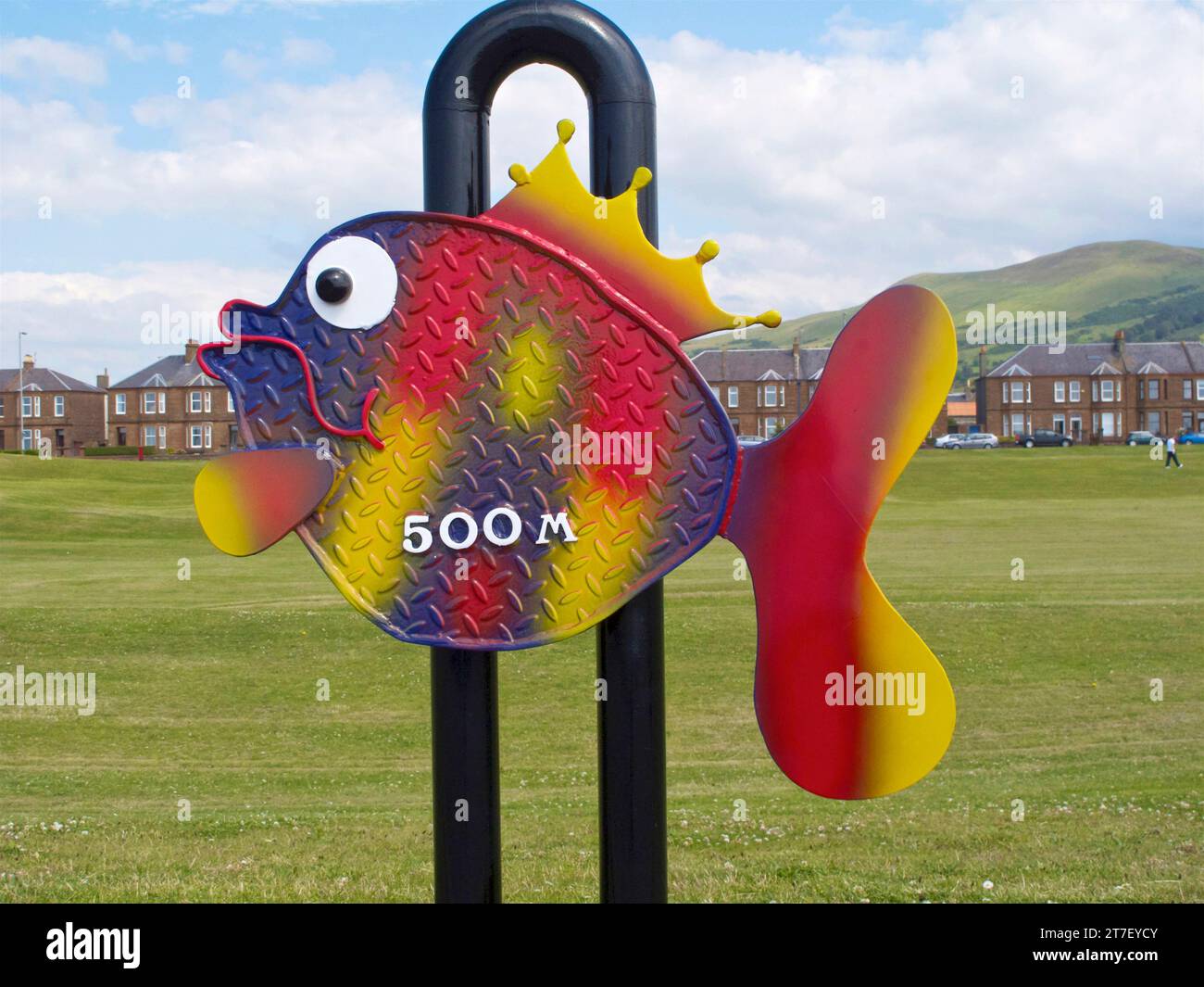 funny fish character distance marker at the beach with grass, houses ...
