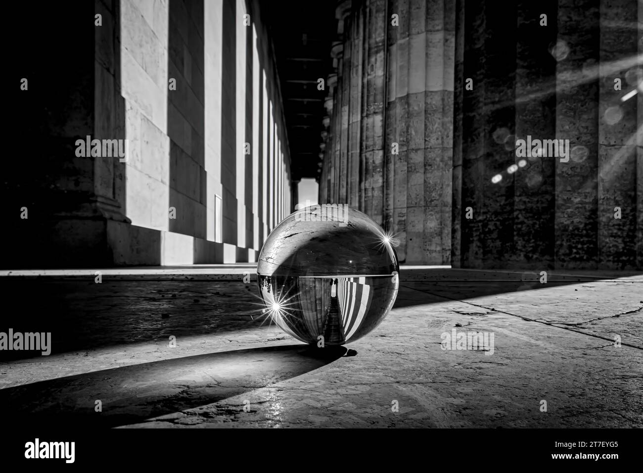 A clear glass sphere lies on the ground of a sunlit indoor space ...