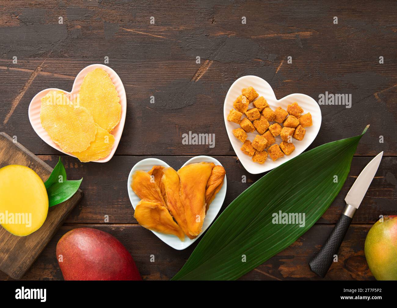 Dried mango slices and balls in heart shaped plates on wooden ...