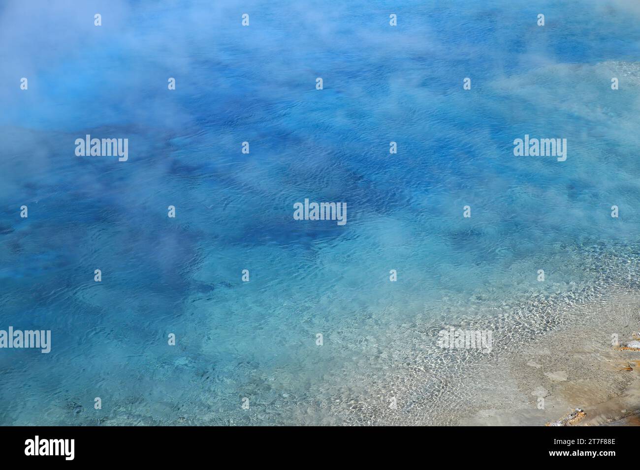 the blue hot spring with steam rising from water in Yellowstone ...