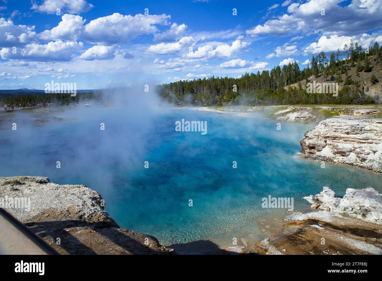 the blue hot spring with steam rising from water in Yellowstone ...