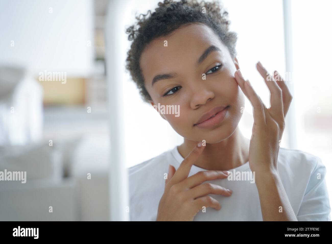 Gentle Black woman touches her face, contemplating beauty in natural ...