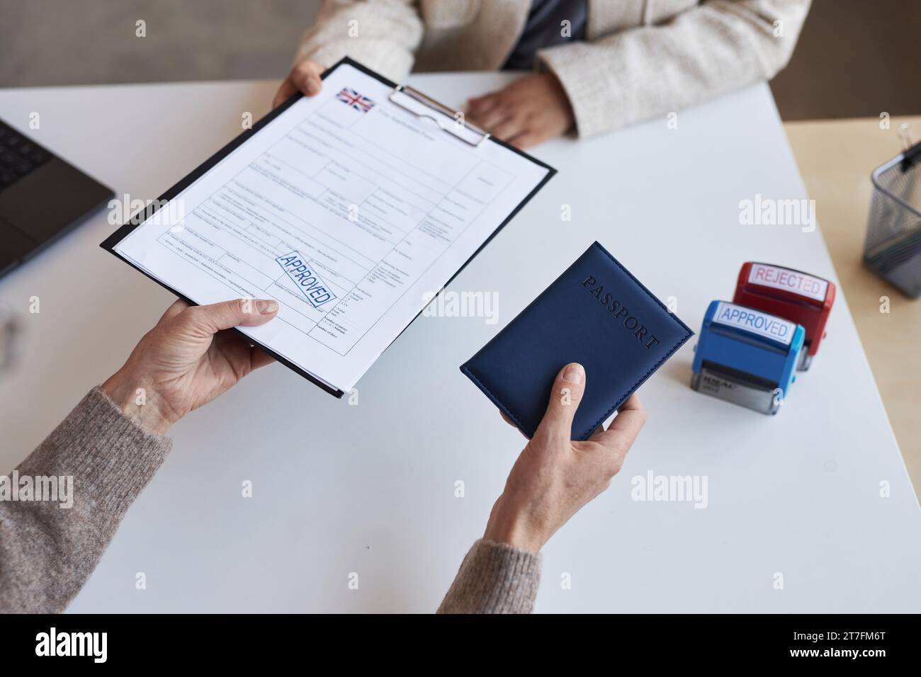 Above angle of female manager passing approved document and passport to ...
