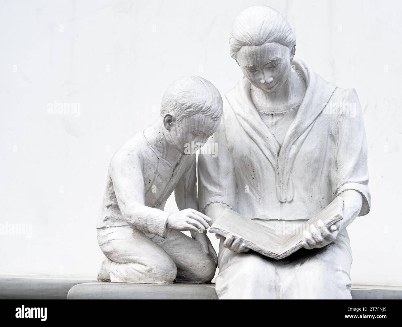An image depicting two statues sitting side-by-side on a bench, with ...