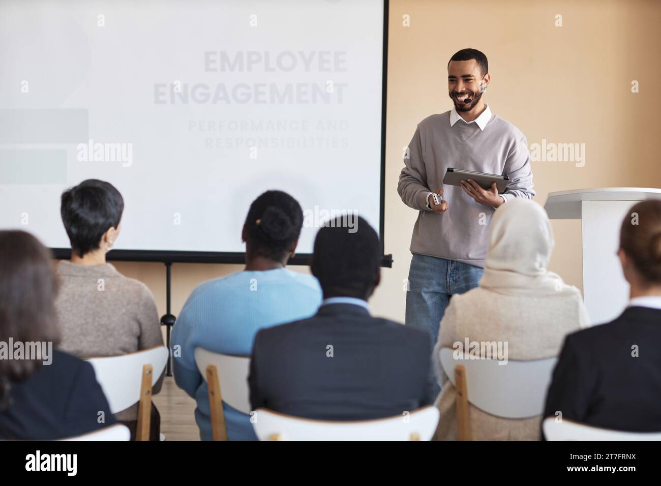 Young cheerful HR manager with tablet looking at one of employees while ...