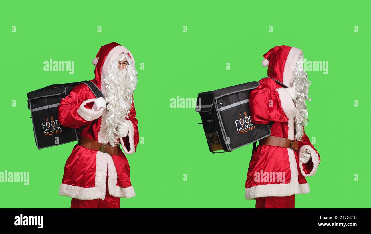 Santa claus carries delivery bag over greenscreen backdrop, working on ...