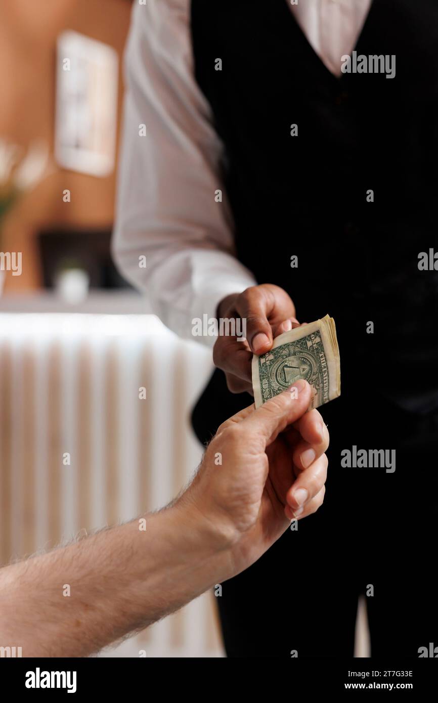 Detailed view of caucasian senior man giving cash to bellhop in ...