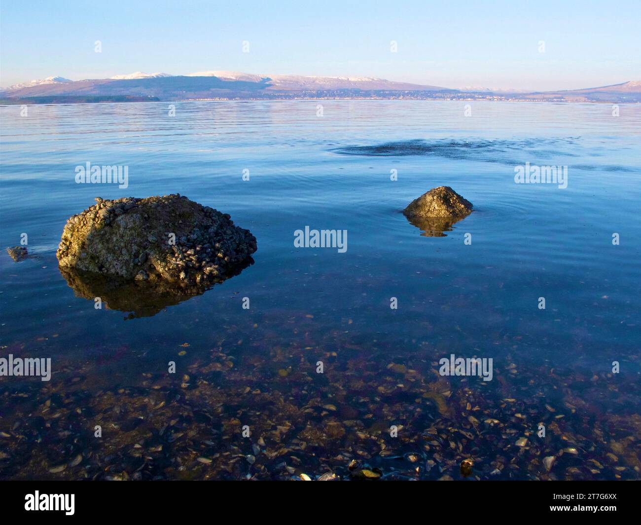 rocks in the blue of the river clyde in greenock in scotland with hills ...