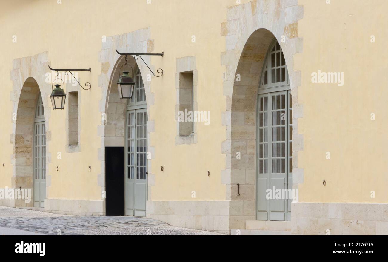 Row of three arched doorways with windows in the doors and lamps ...