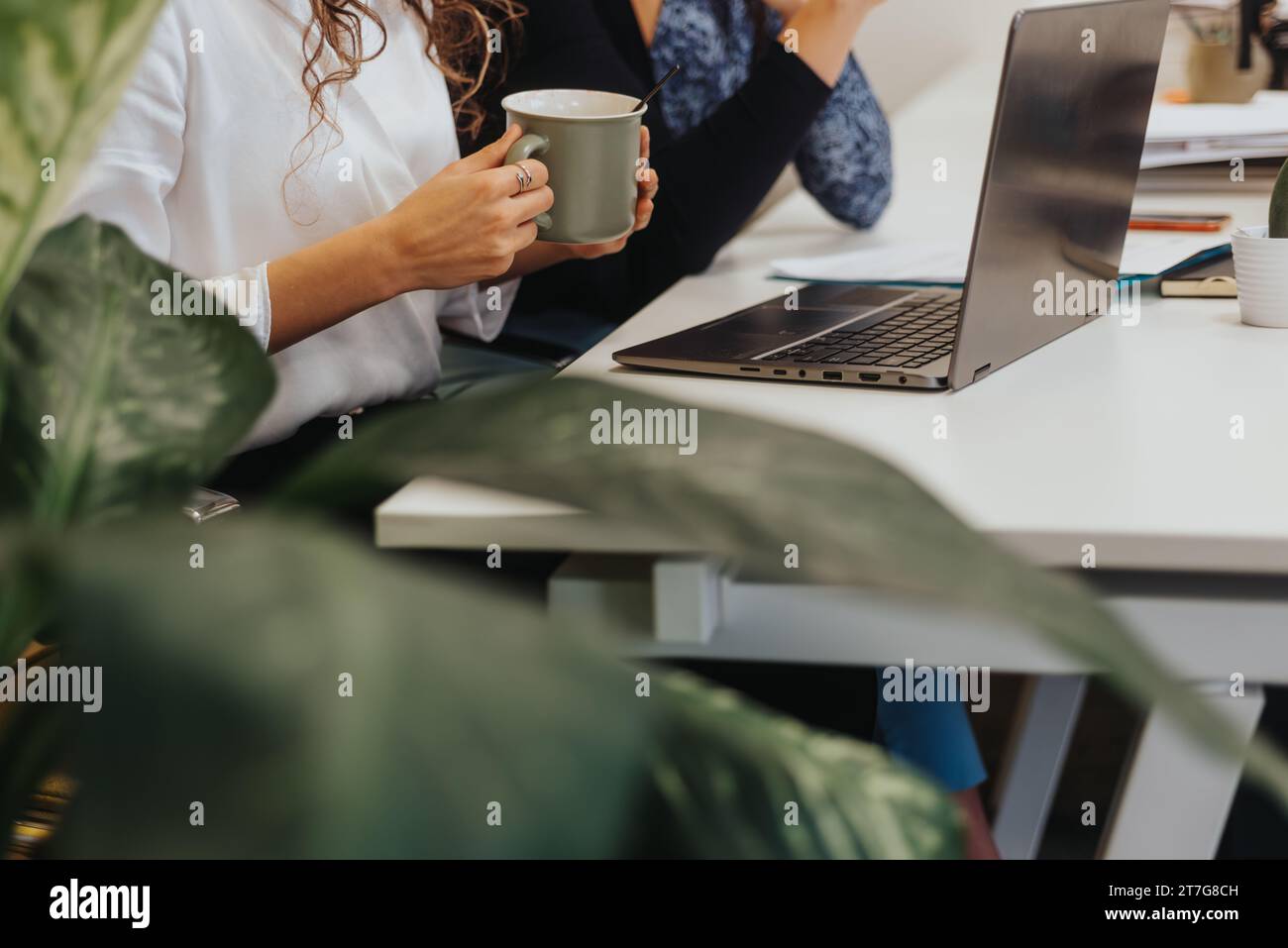 Female employees enjoying tea or coffee while working together at ...
