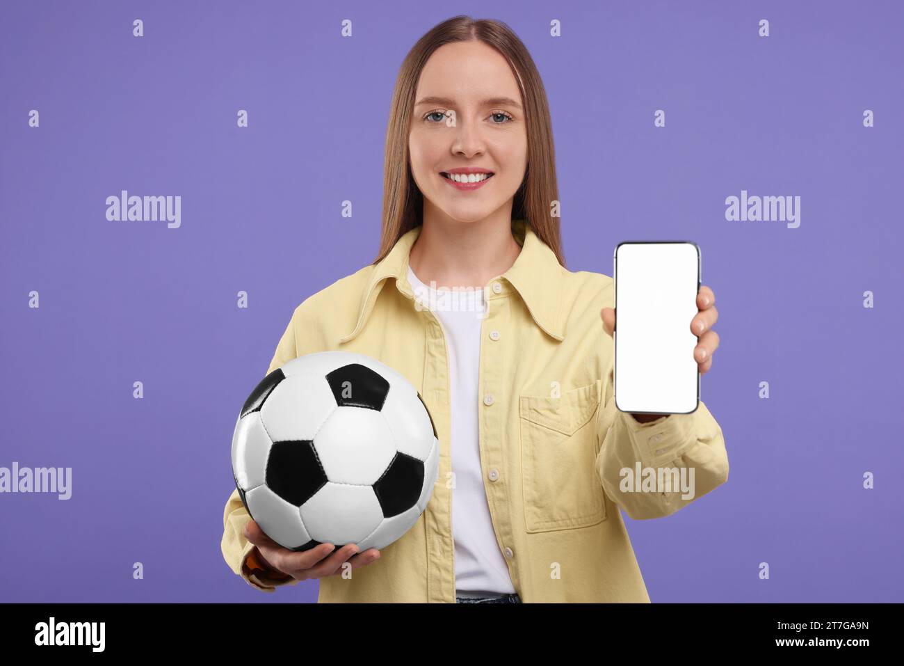 Happy sports fan with ball and smartphone on purple background Stock ...