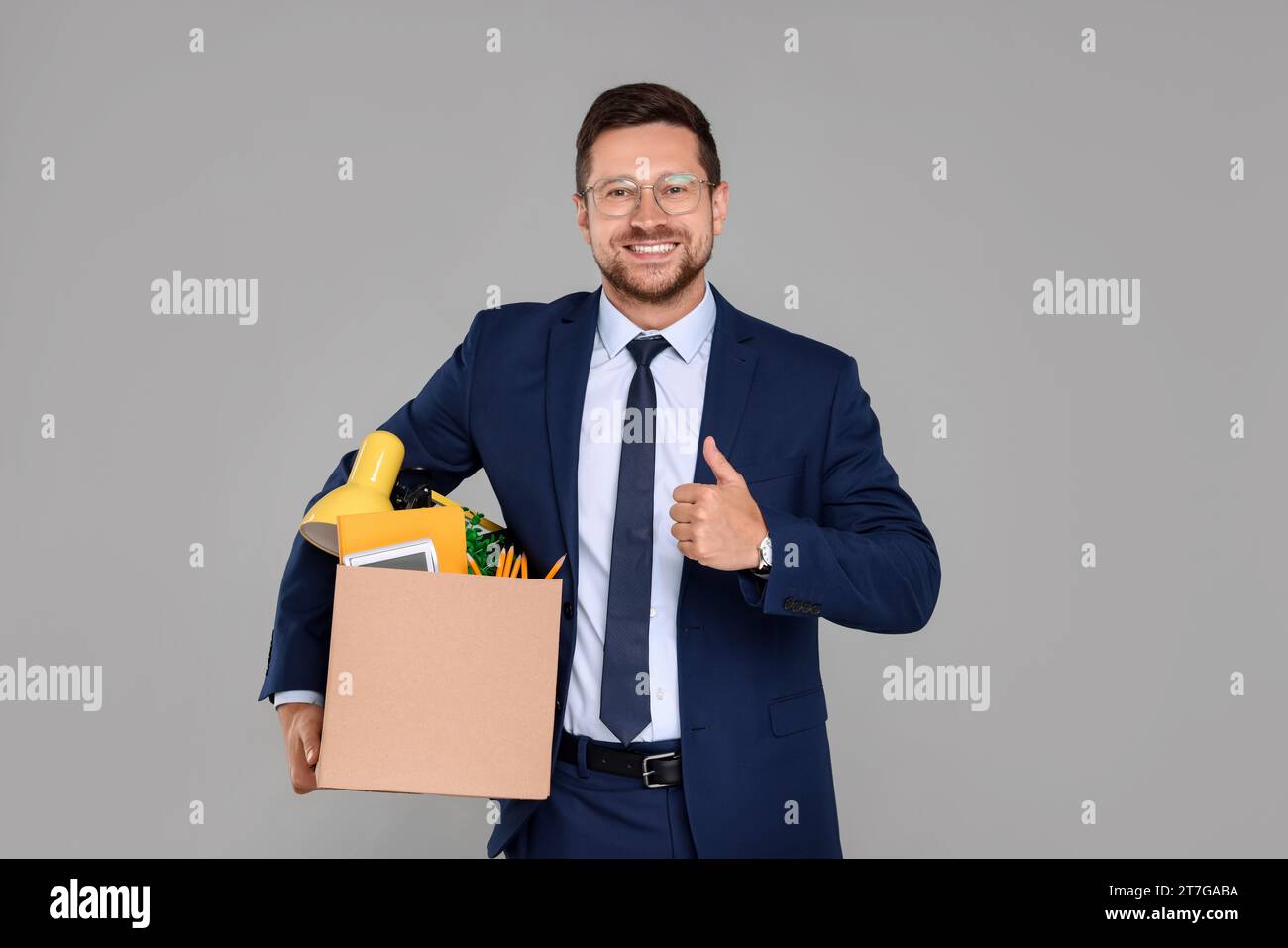 Happy unemployed man with box of personal office belongings showing ...