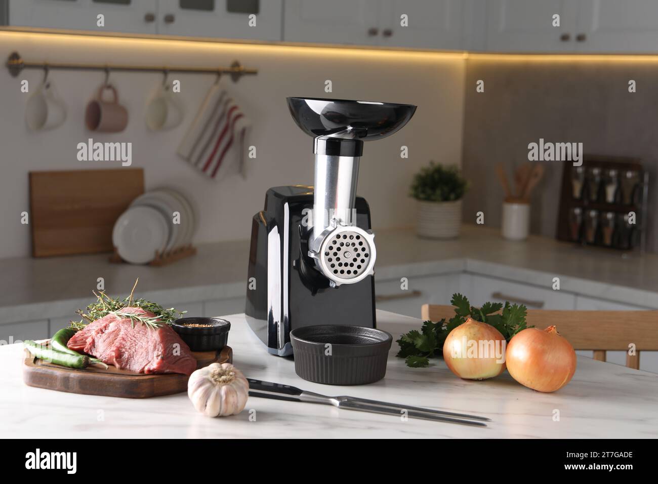 Electric meat grinder with beef mince and products on white marble ...