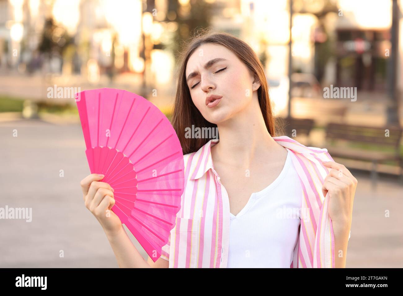 Woman with hand fan suffering from heat outdoors Stock Photo - Alamy