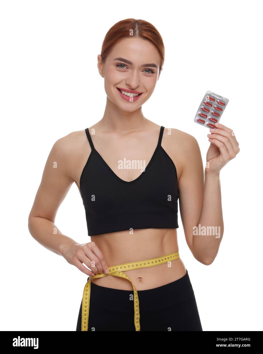 Slim woman holding pills and measuring waist with tape on white ...