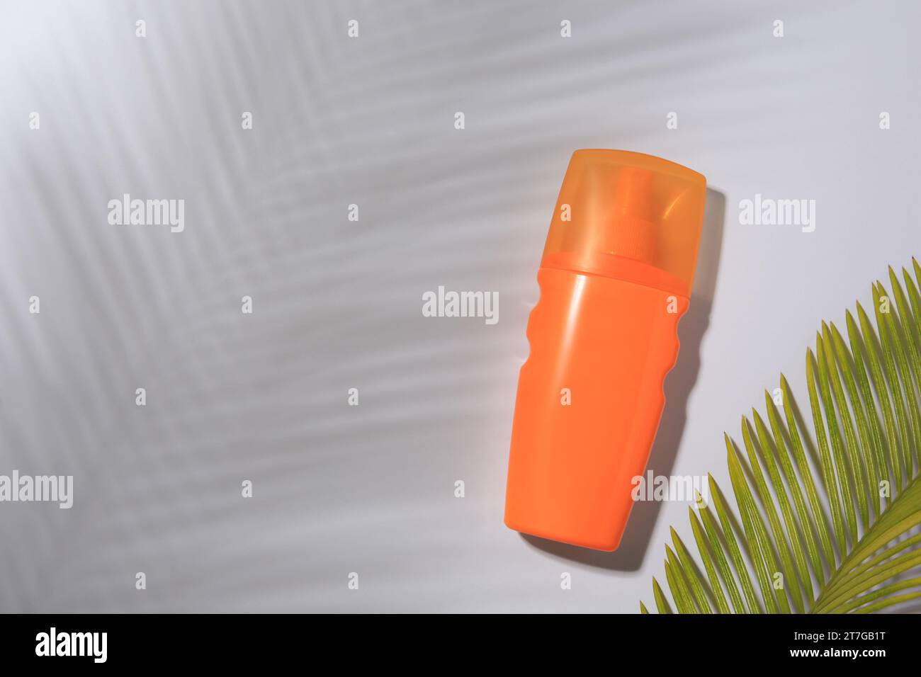 Sunscreen and tropical leaf on white background, flat lay and space for ...