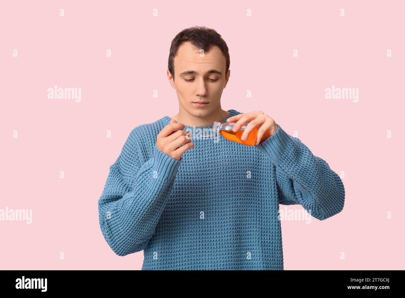 Ill young man taking cough syrup on pink background Stock Photo - Alamy