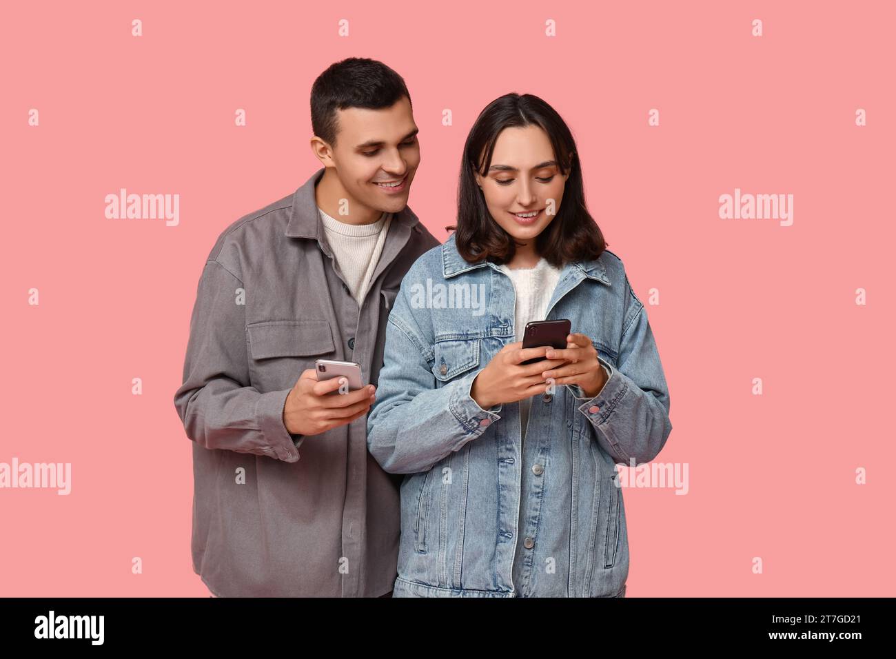 Happy young couple with mobile phones on pink background Stock Photo ...