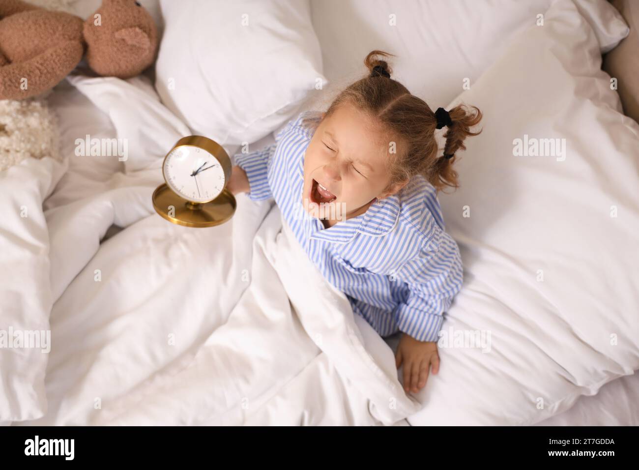 Little girl with alarm clock screaming in bed, top view Stock Photo - Alamy