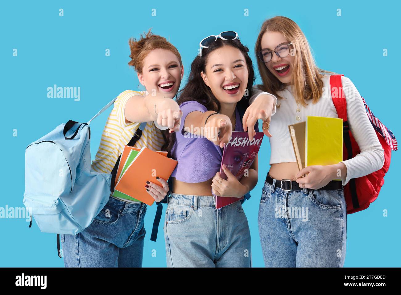 laughing female students pointing at viewer on blue background Stock ...