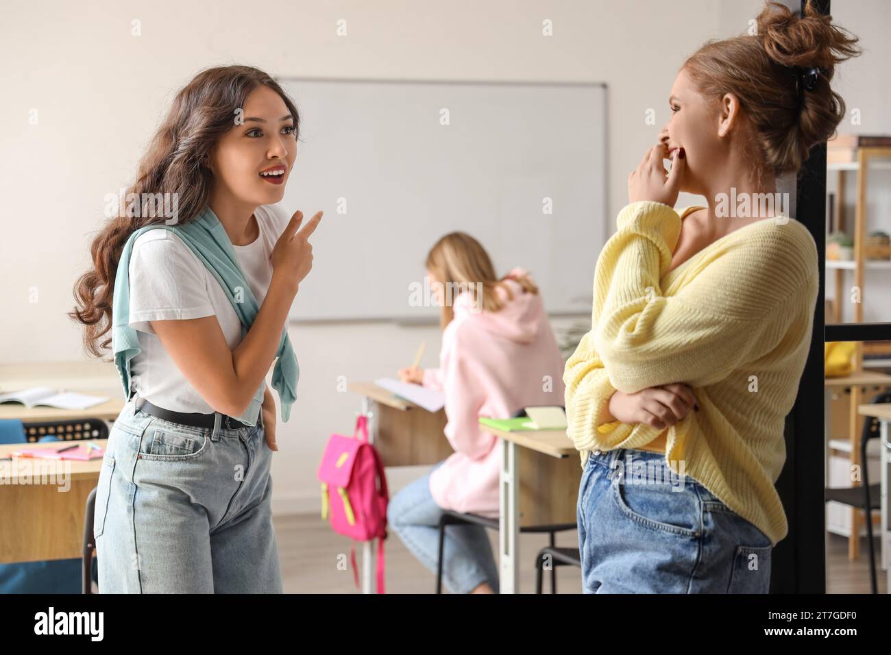 Female students gossiping about their classmate in classroom Stock ...