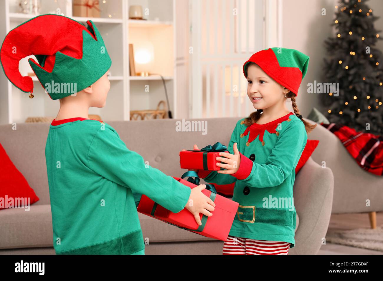 Cute little children in elf costumes with gifts at home on Christmas ...
