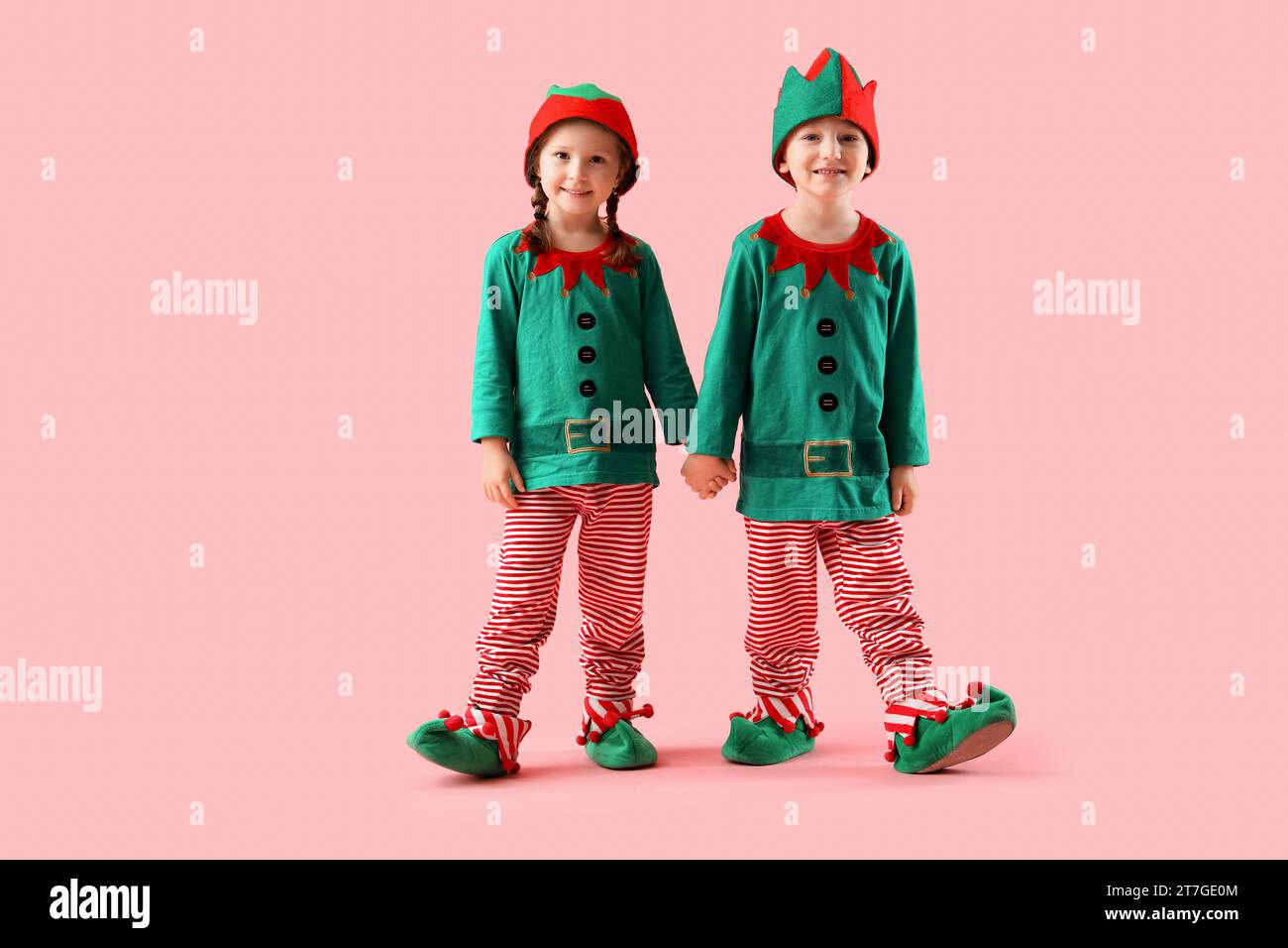 Cute little elves holding hands on pink background Stock Photo - Alamy