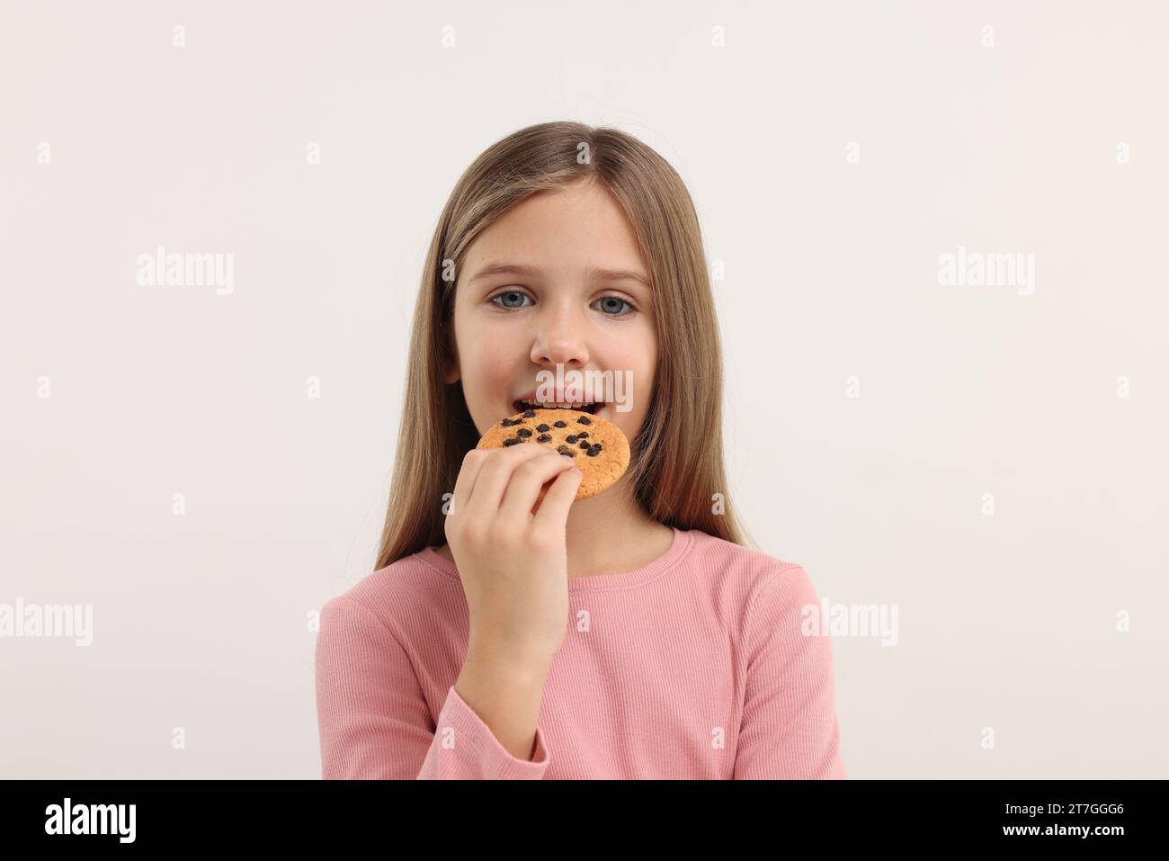 Cute girl eating chocolate chip cookies on white background Stock Photo ...