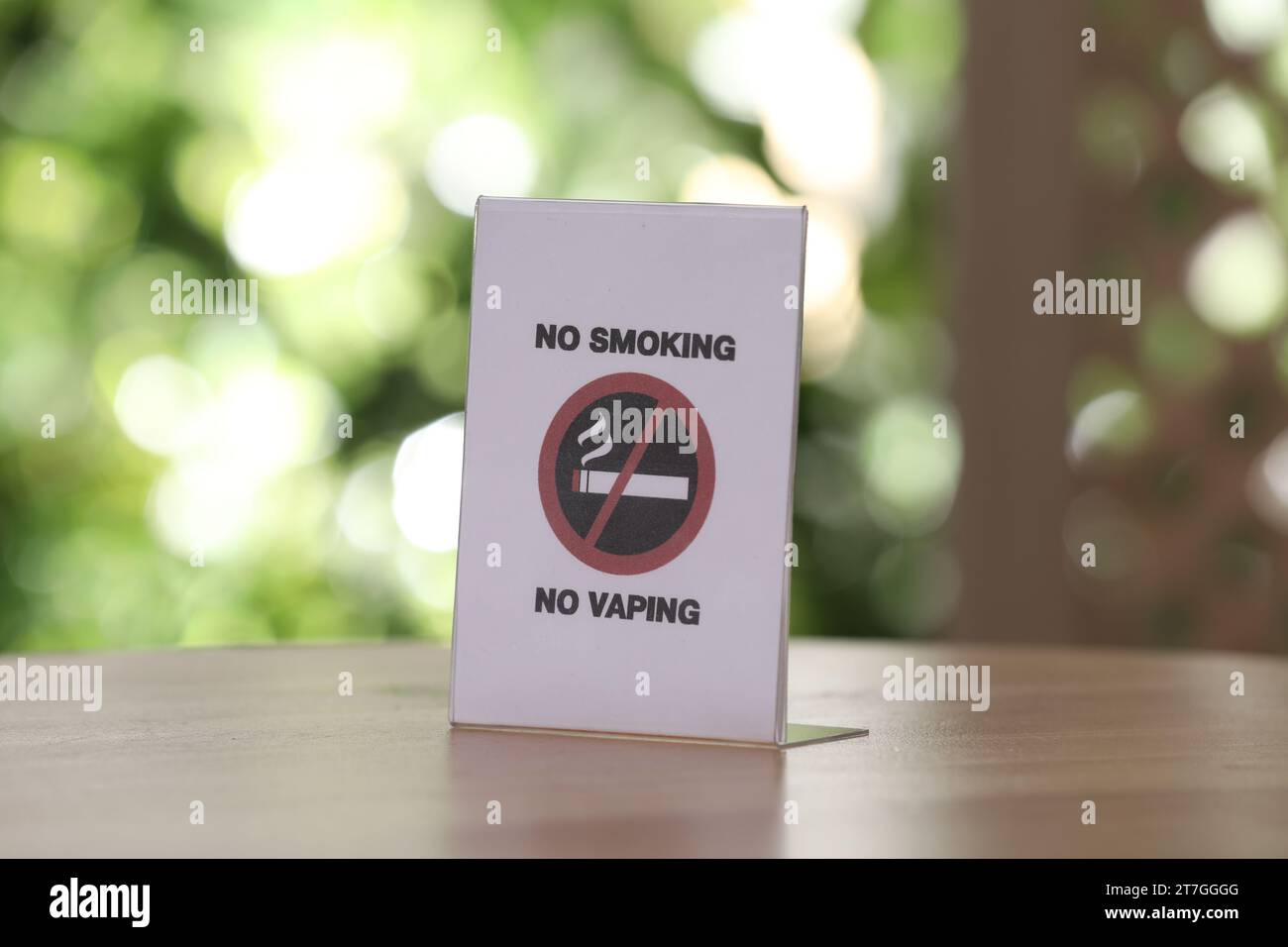 No Smoking No Vaping sign on wooden table against blurred background ...