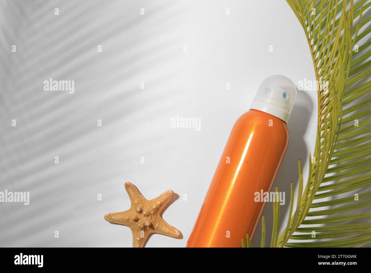 Sunscreen, starfish and tropical leaf on white background, flat lay and ...