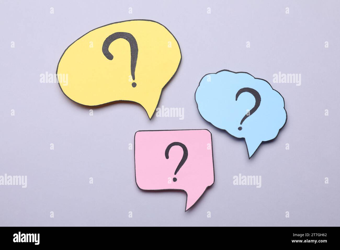 Different paper speech bubbles with question marks on light grey ...