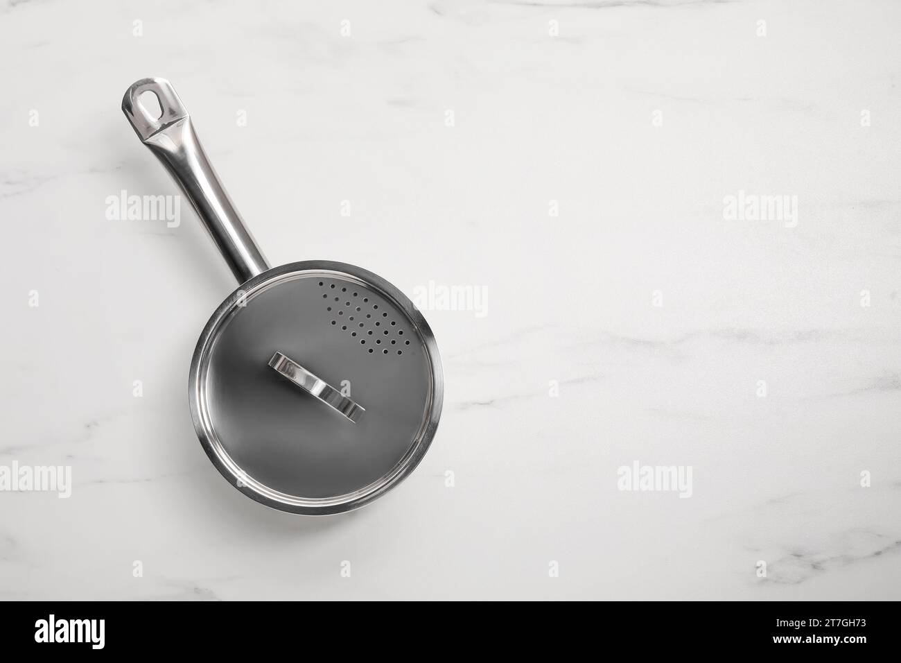 One steel saucepan with strainer lid on white marble table, top view ...